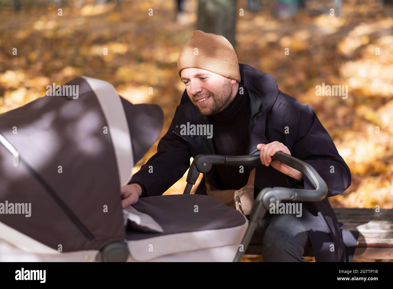 Happy young father with pram sitting on bench in nature at park Stock ...