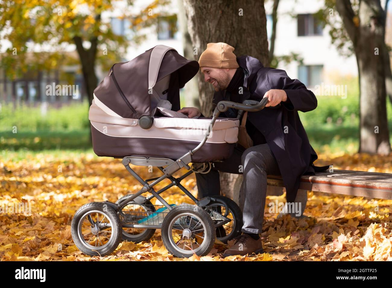 Happy young father with pram sitting on bench in nature at park Stock ...