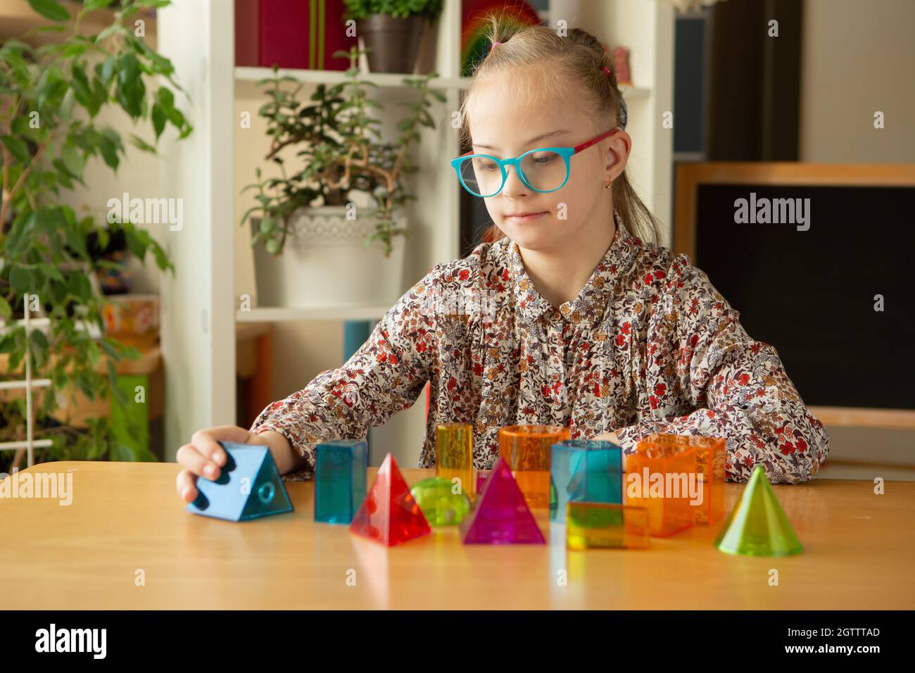 Girl with Down Syndrome studying geometric shapes Stock Photo - Alamy