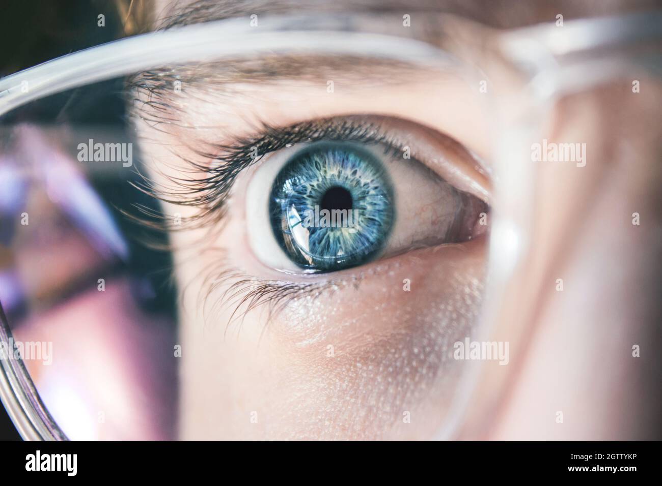 Closeup shot of a blue human eye wearing optical glasses, Ophthalmology ...