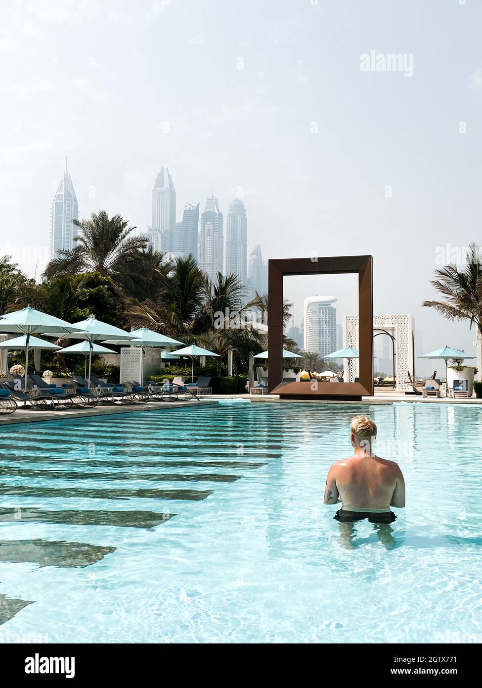 Man in dipping in a pool resort with a hazy skyline in the background ...