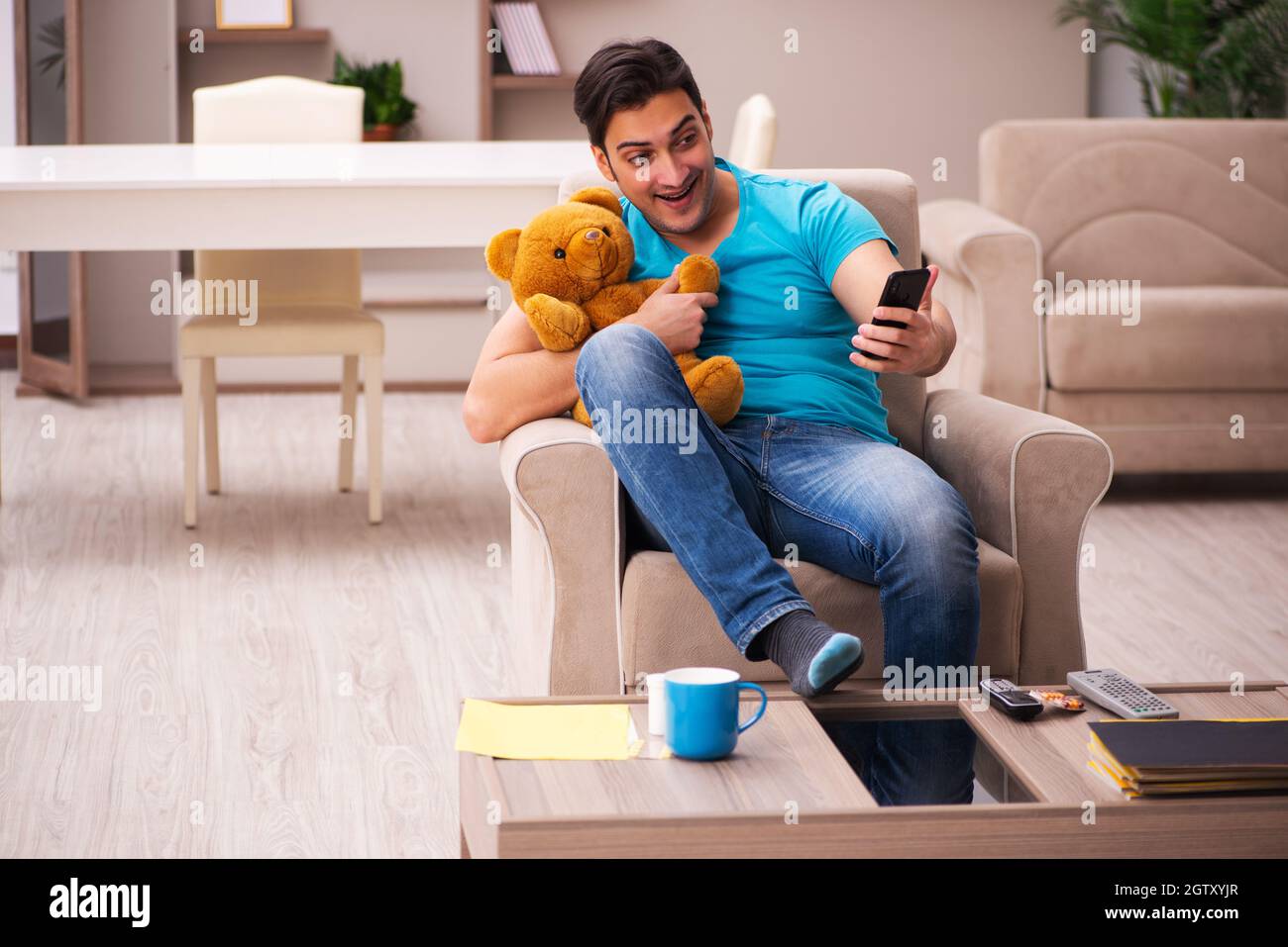Young man and bear toy at home Stock Photo - Alamy