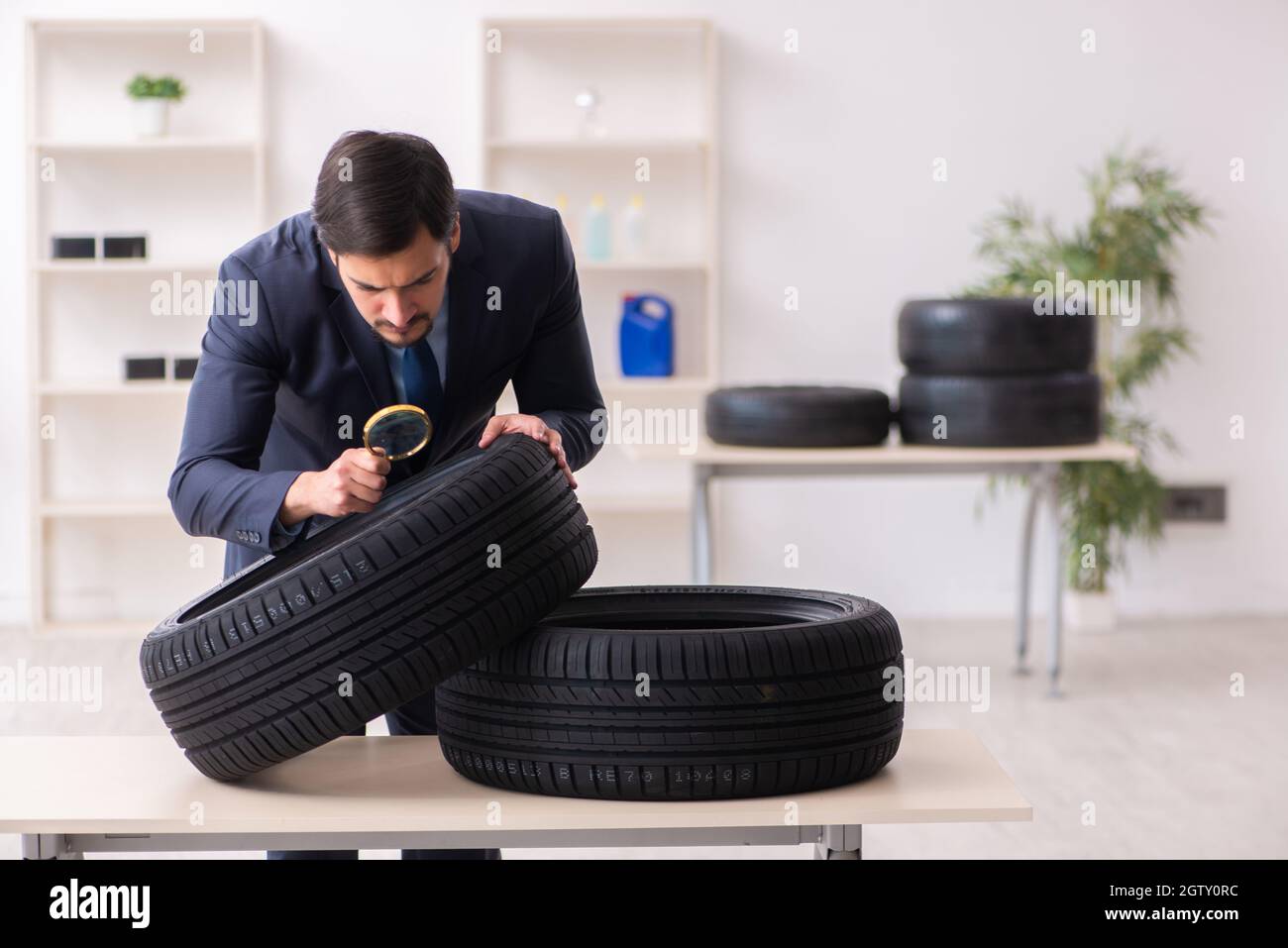 Young businessman inspecting tires in the office Stock Photo - Alamy