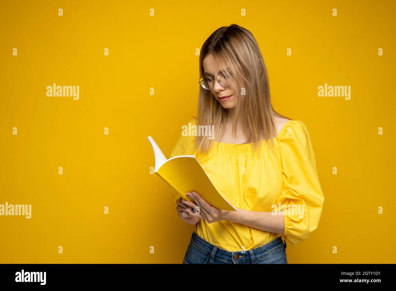 Beautiful smart young girl holding and reading book isolated on the ...
