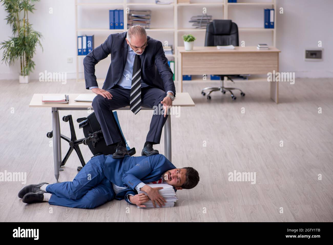 Old boss and young employee in bullying concept Stock Photo - Alamy