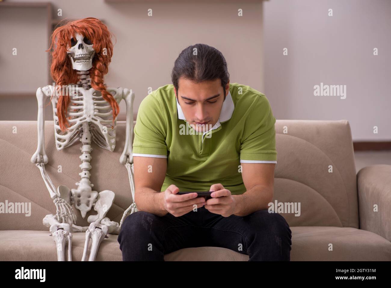 Man sitting on the sofa with female skeleton Stock Photo - Alamy