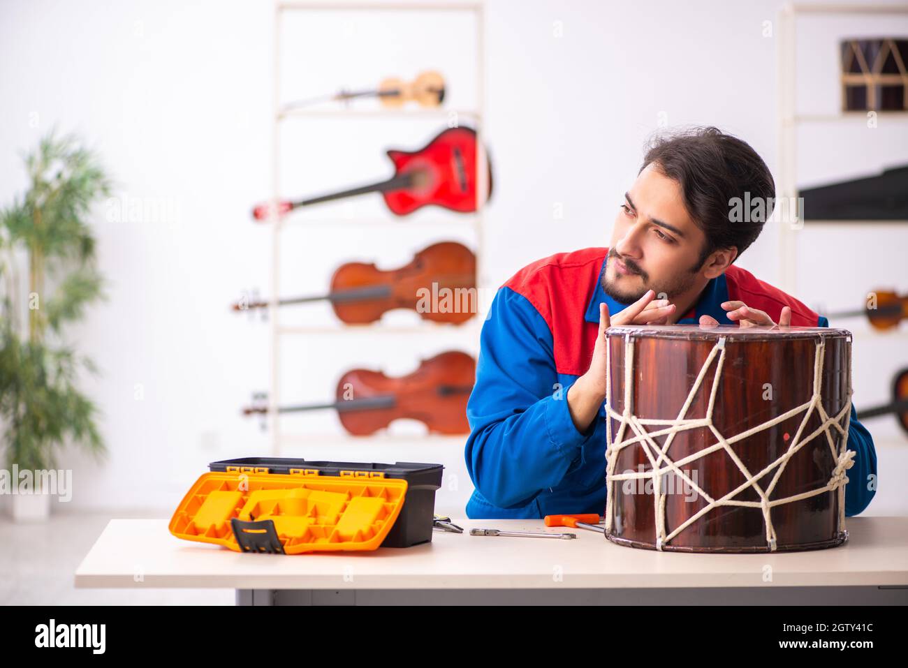 Young repairman repairing musical instruments at workplace Stock Photo ...