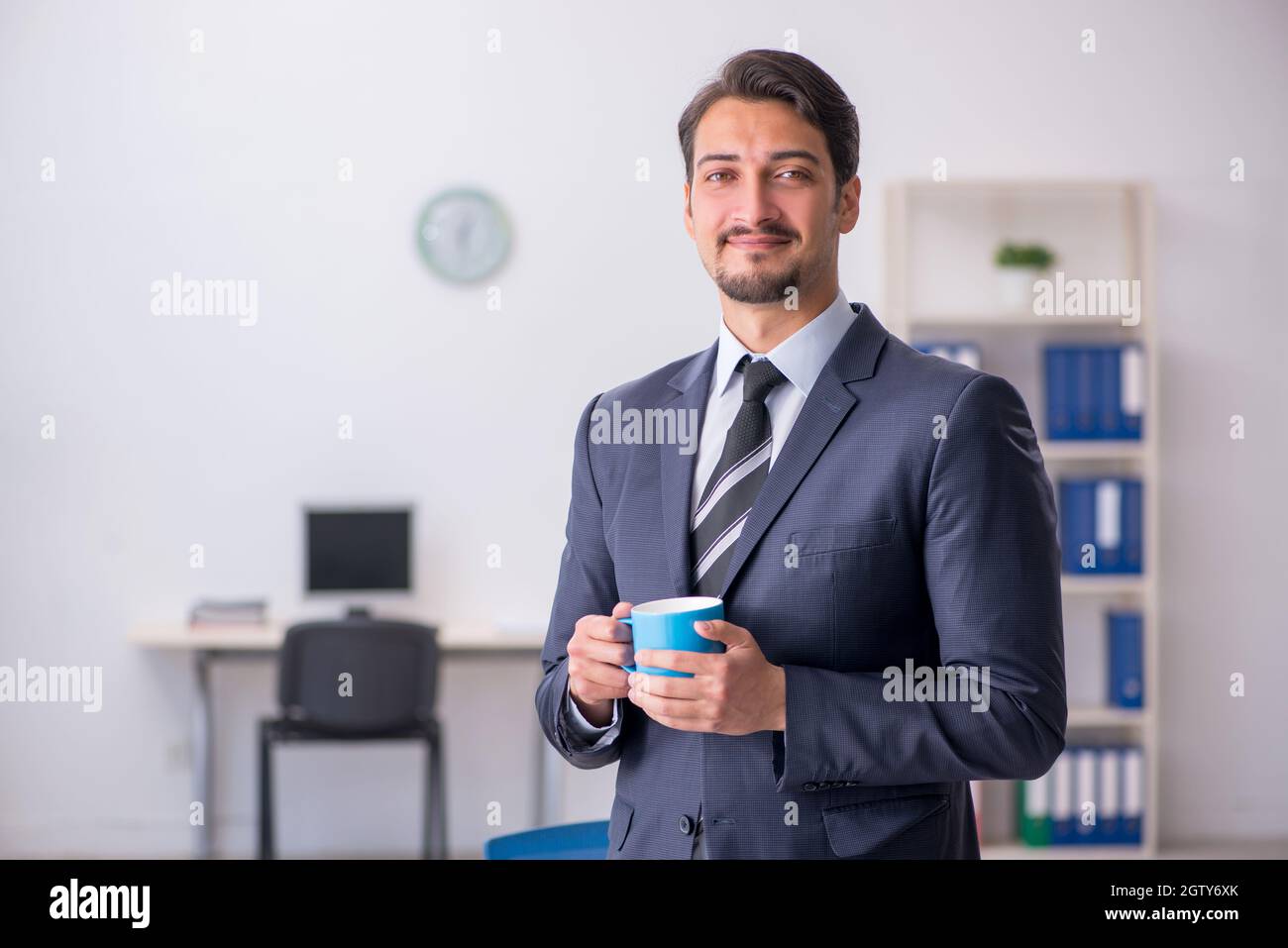 Young businessman employee drinking coffee during break Stock Photo - Alamy