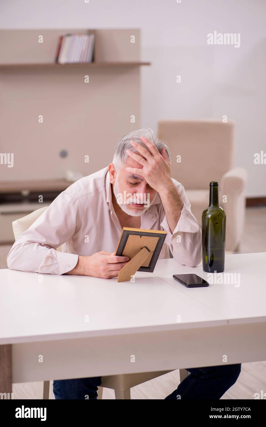 Aged widower drinking alcohol at home Stock Photo - Alamy