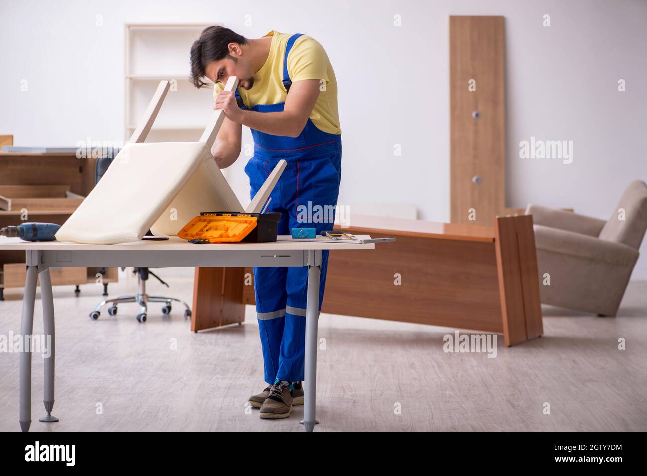 Young carpenter repairing chair in the office Stock Photo - Alamy