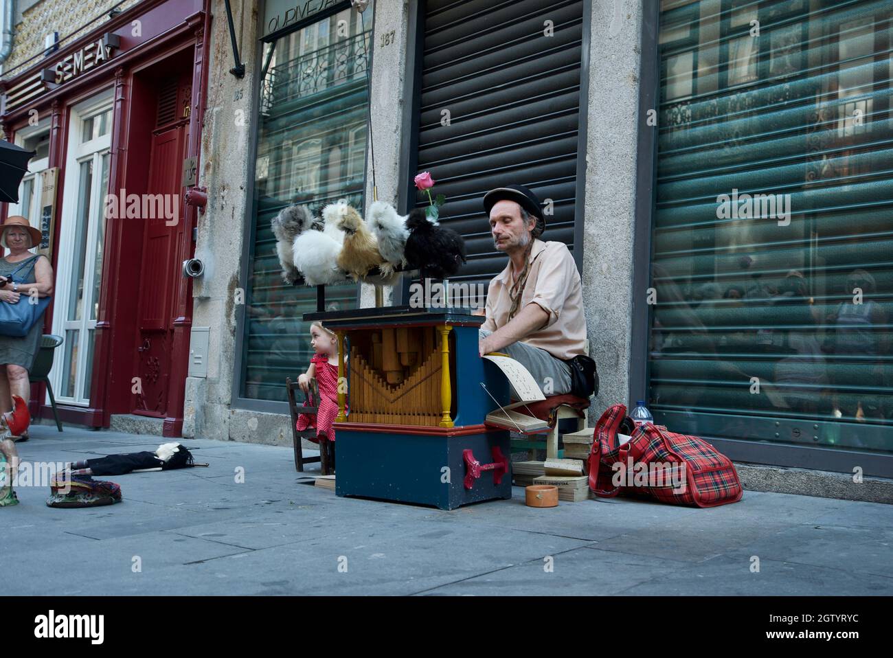 Busker playing a card based music box with chickens at Rua das Flores ...