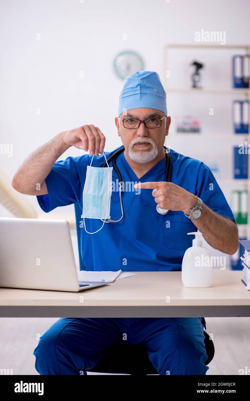 Old doctor working in the clinic during pandemic Stock Photo - Alamy