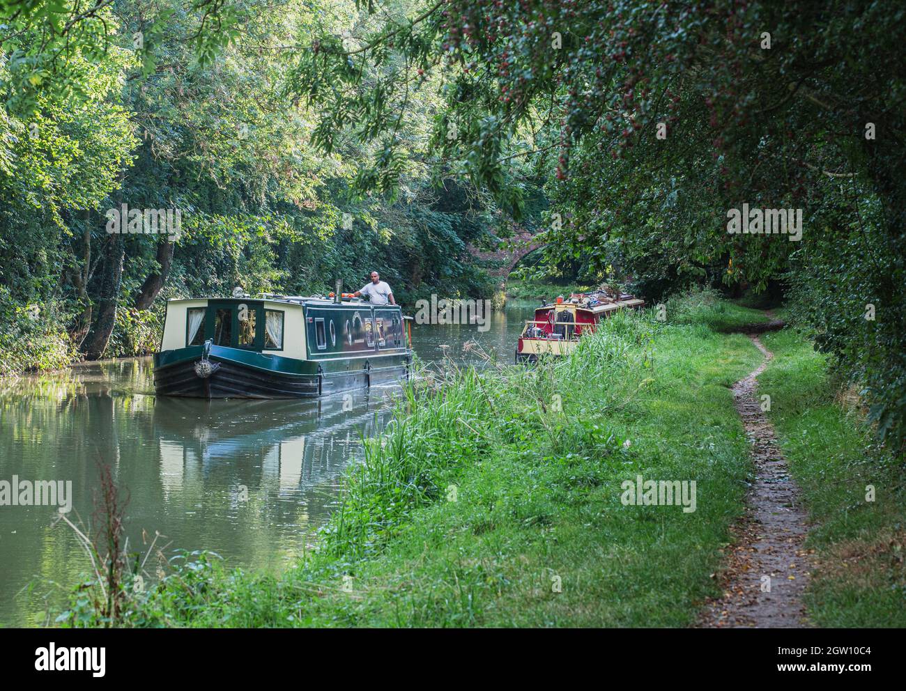 A green coloured narrow boat moving along the Kennet and Avon Canal ...