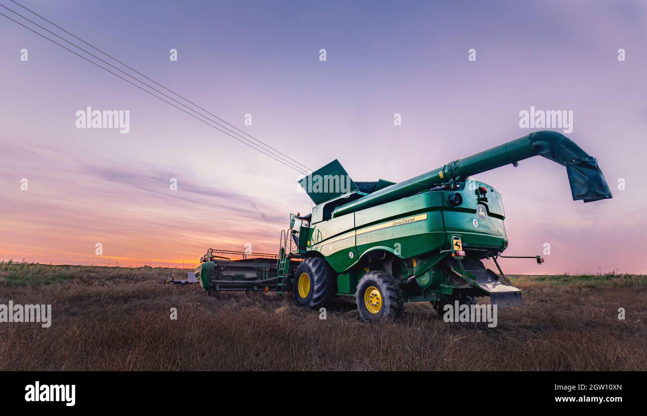combine harvester standing alone in field in Wiltshire, UK at sunset ...