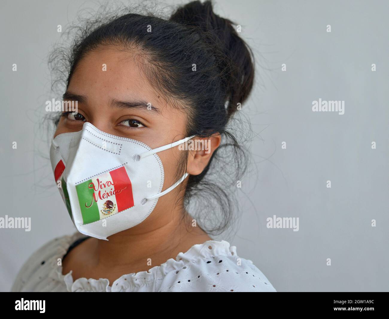 Brown eyed patriotic pretty Mexican girl wears a KN95-style face mask ...
