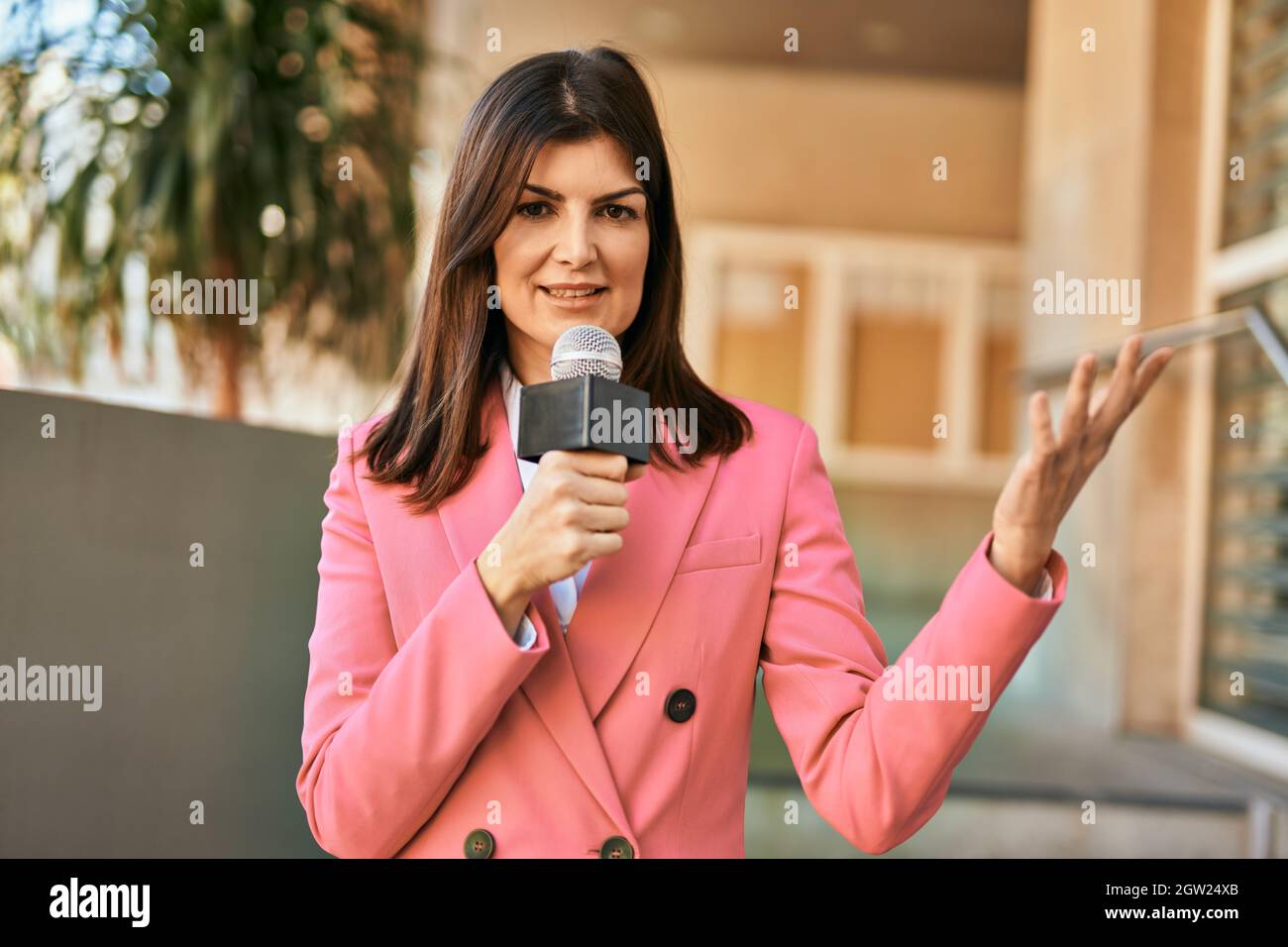 Middle age reporter woman holding microphone doing television speech ...