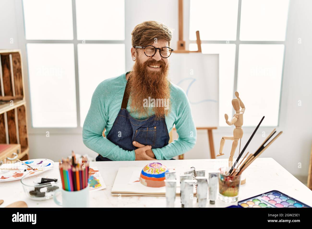 Redhead man with long beard painting clay bowl at art studio with hand ...