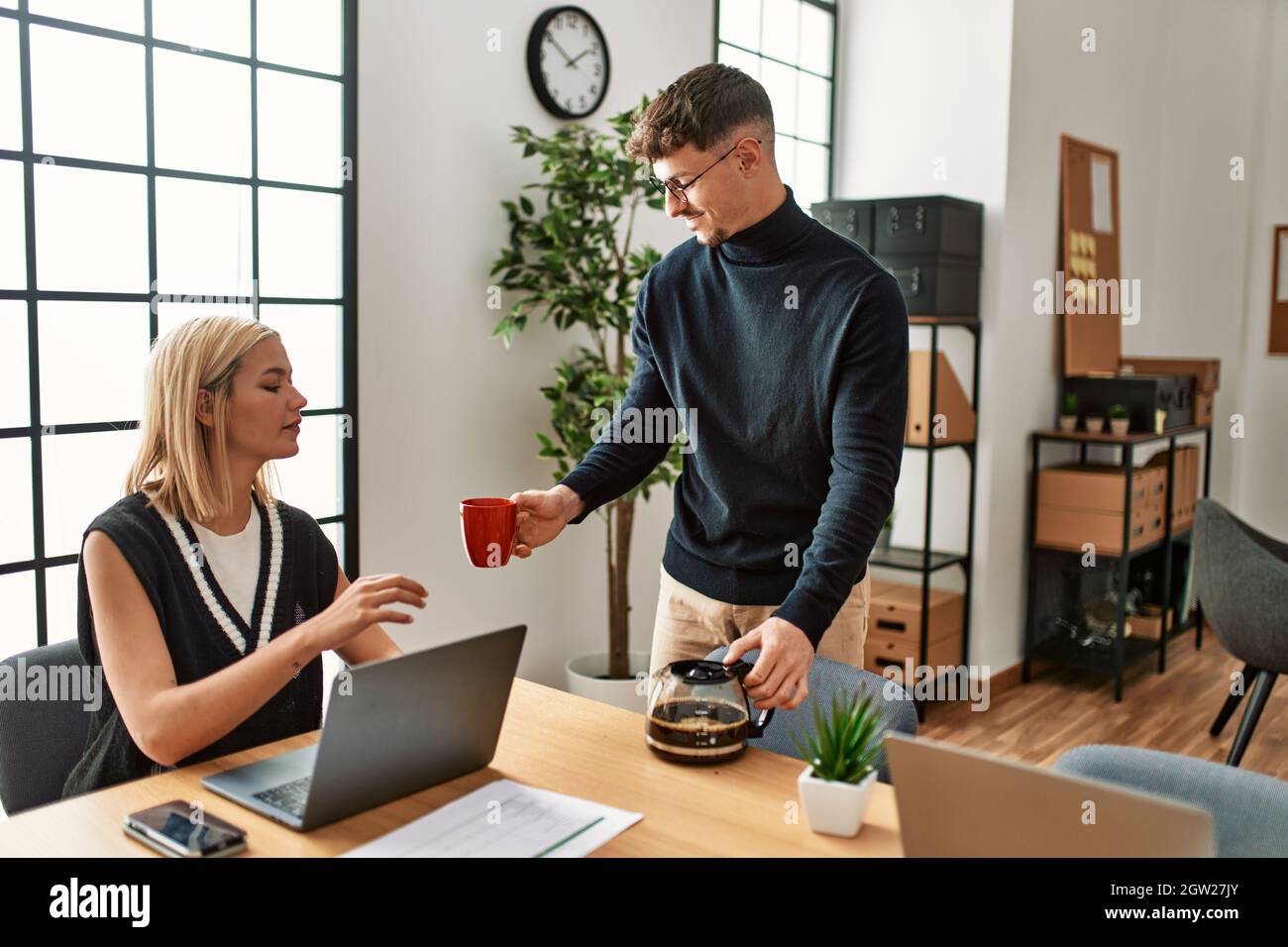 Two business workers smiling happy working and drinking coffee at the ...