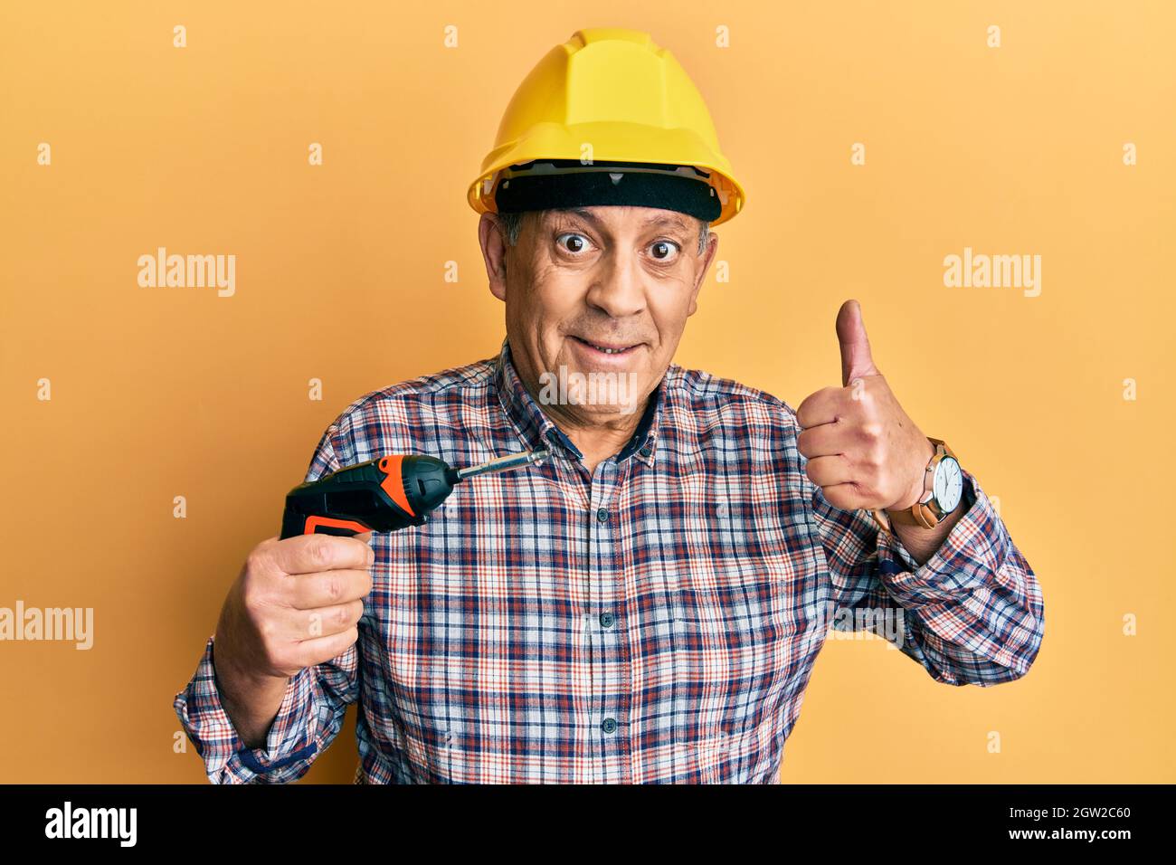 Handsome senior man with grey hair holding screwdriver wearing hardhat ...