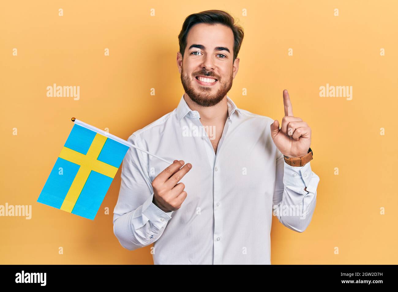 Handsome caucasian man with beard holding sweden flag smiling with an ...
