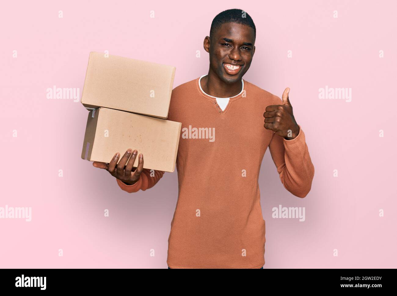 Young african american man holding delivery package smiling happy and ...