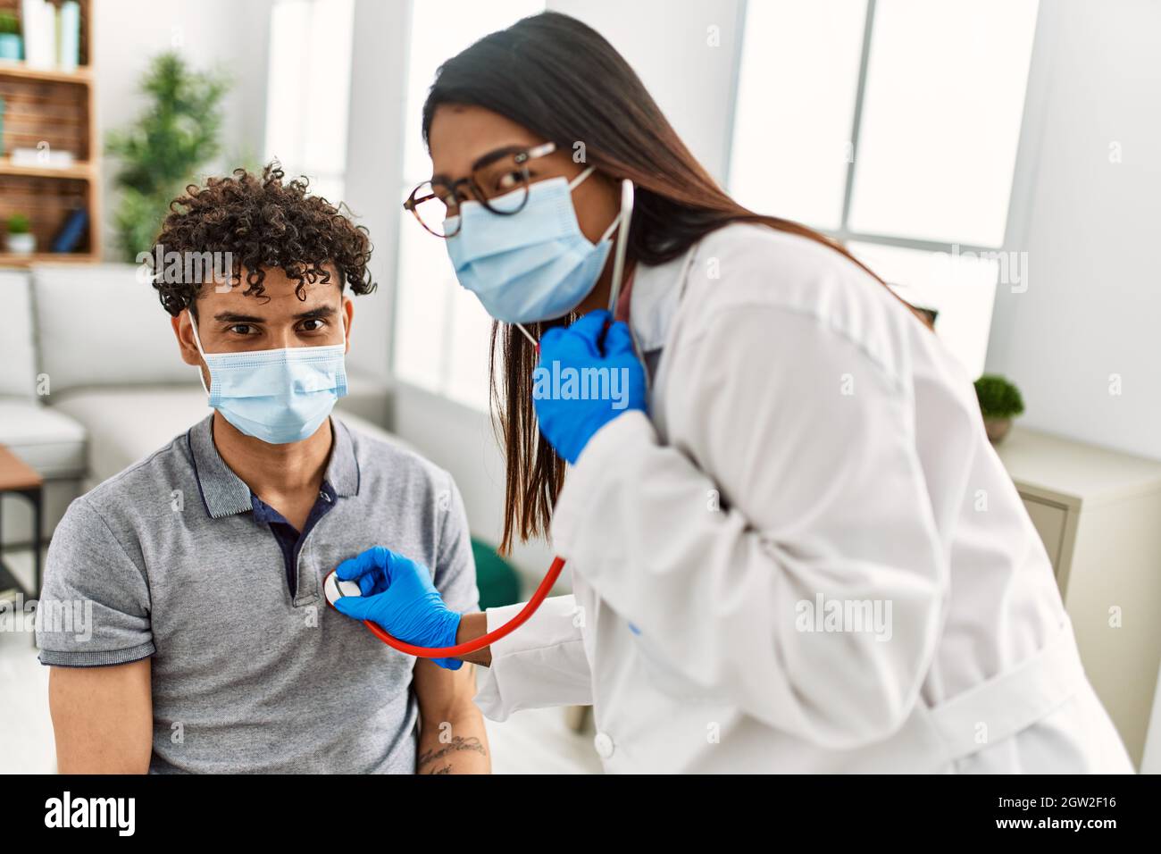 Young latin doctor woman auscultate heart man using stethoscope at ...