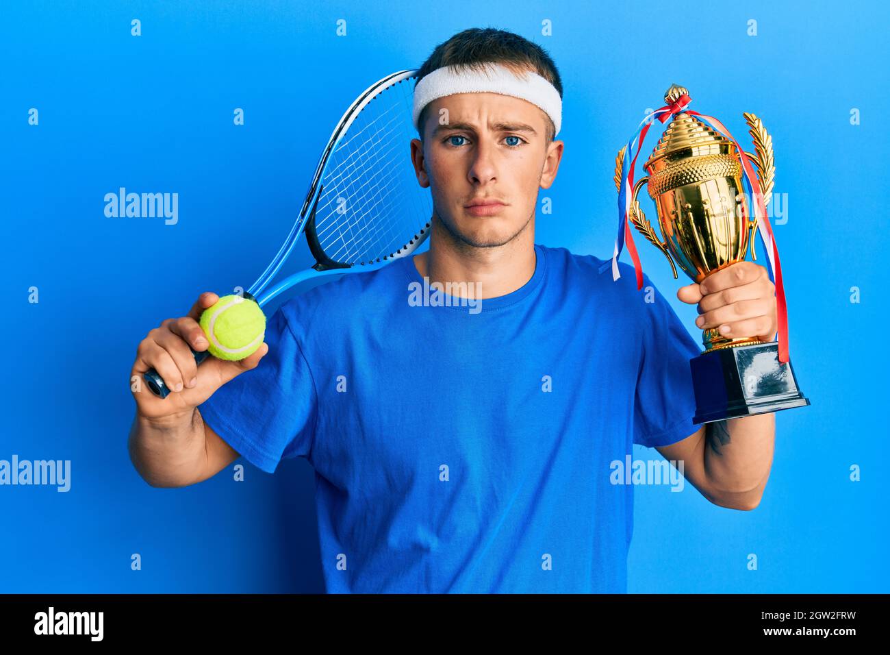 Young caucasian man playing tennis holding trophy depressed and worry ...