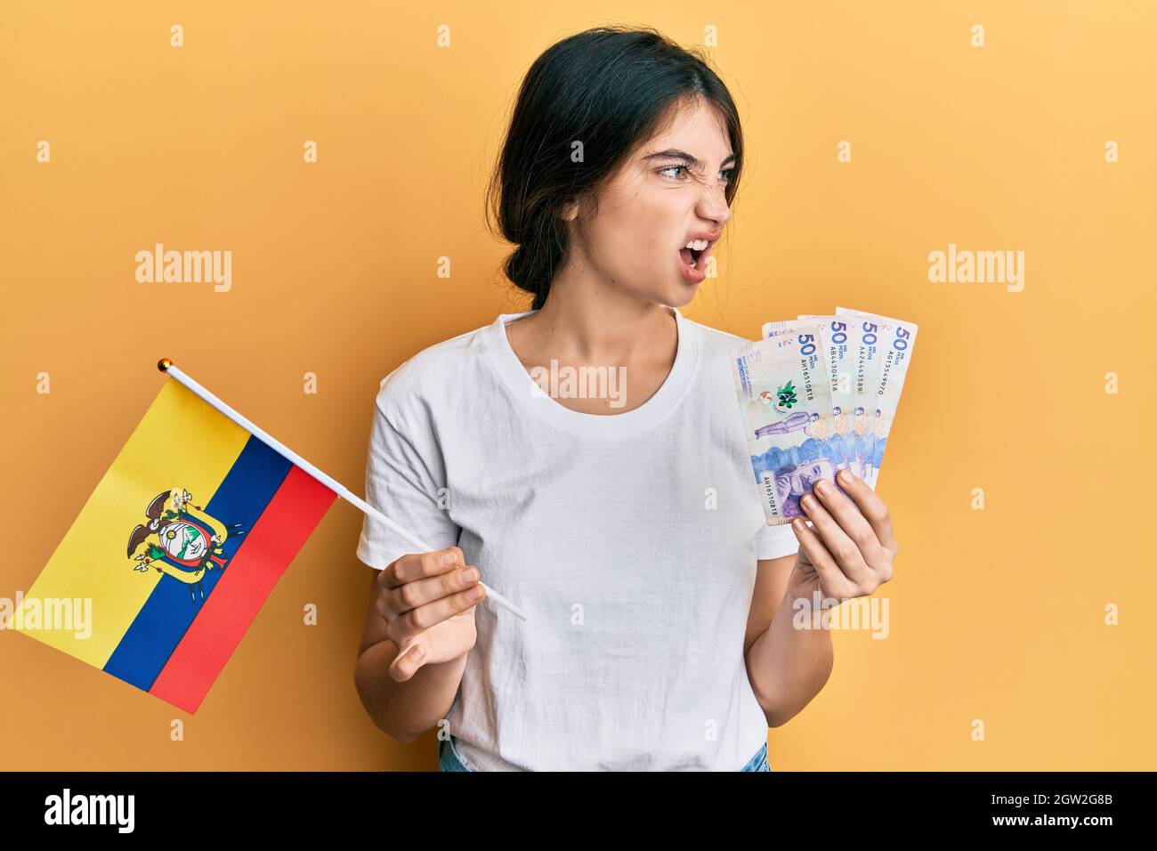 Young caucasian woman holding colombia flag and colombian pesos ...