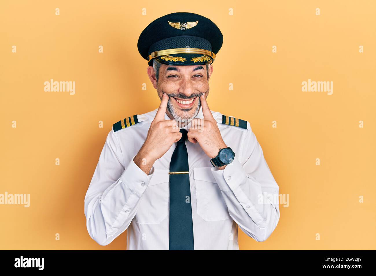 Handsome middle age man with grey hair wearing airplane pilot uniform ...
