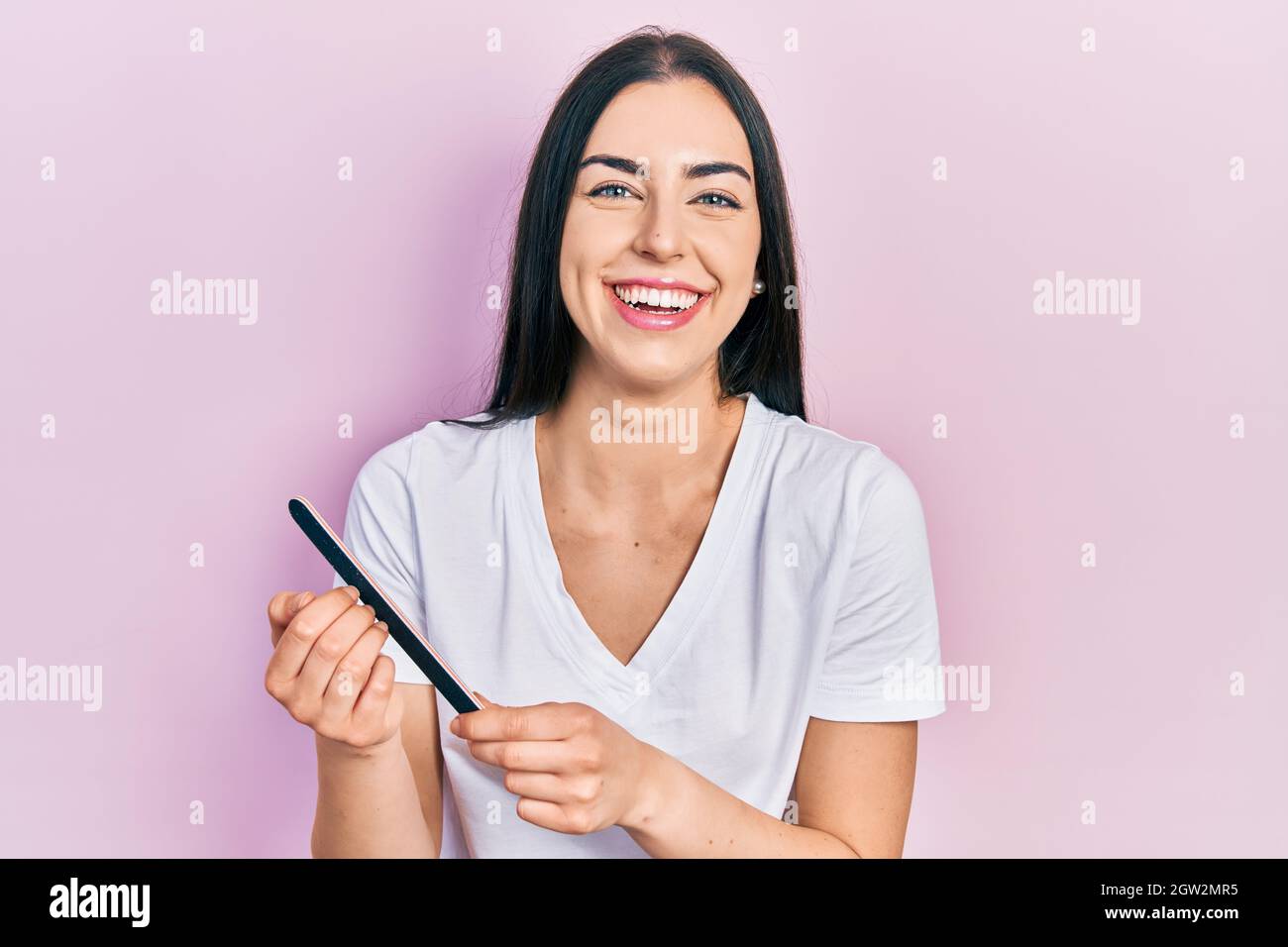 Beautiful woman with blue eyes using file nail smiling and laughing hard out loud because funny ...