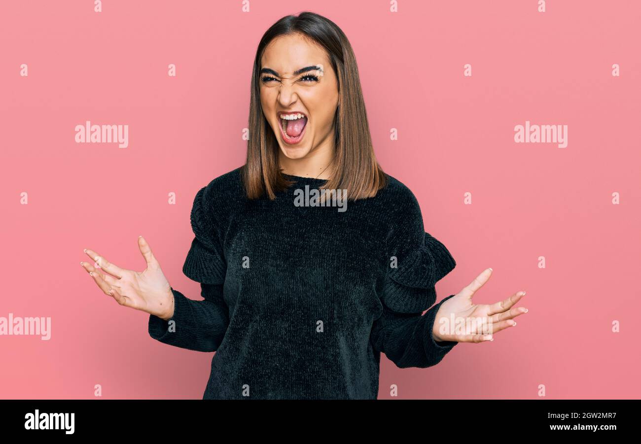 Beautiful brunette woman wearing elegant sweater crazy and mad shouting ...