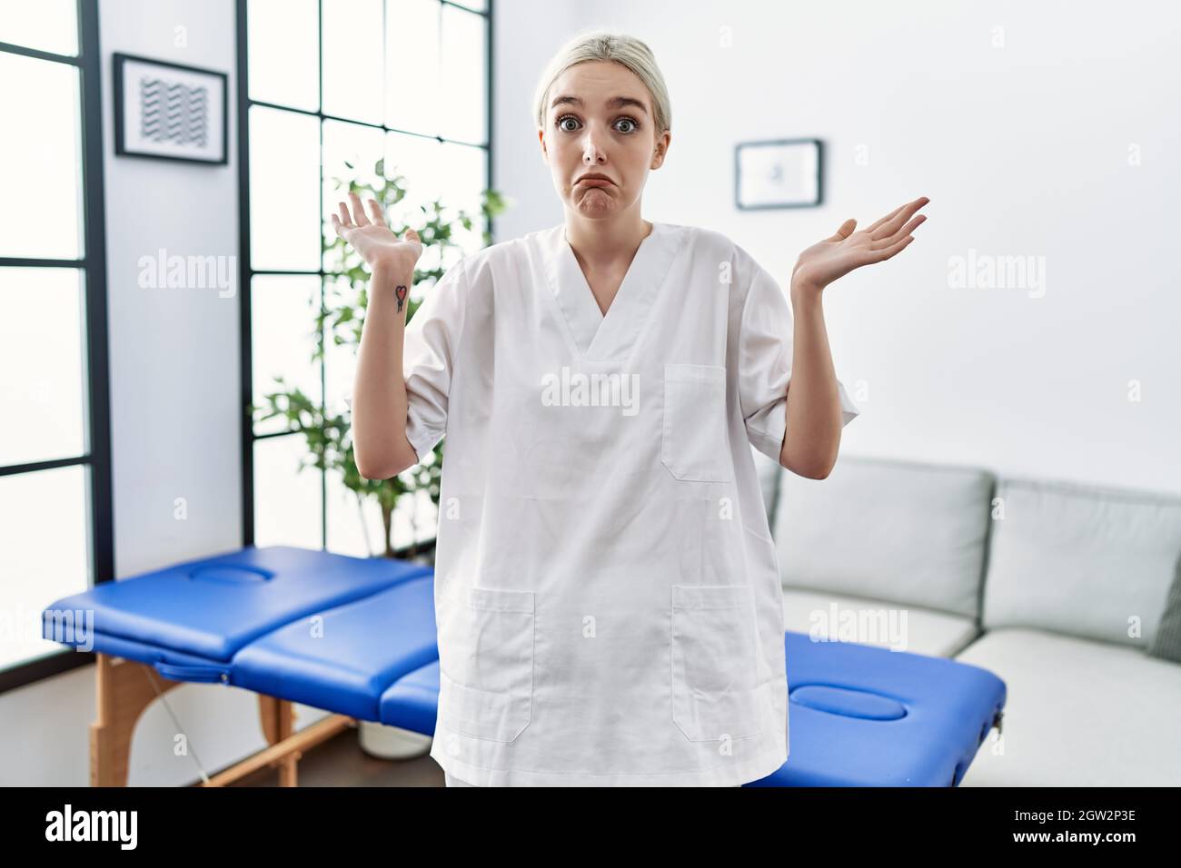 Young caucasian physiotherapy woman working at home clueless and ...