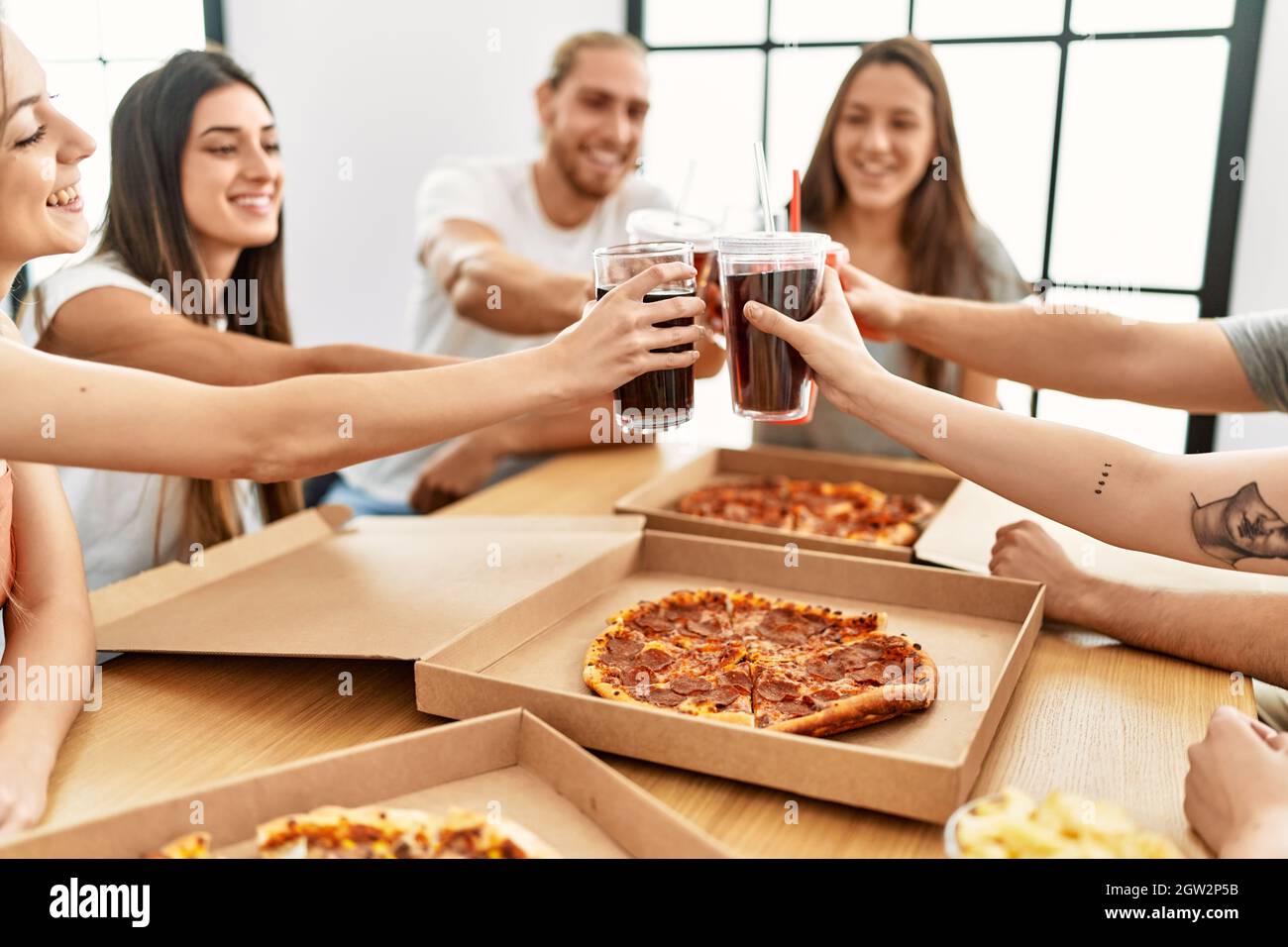 Group of young friends smiling happy eating italian pizza and toasting ...