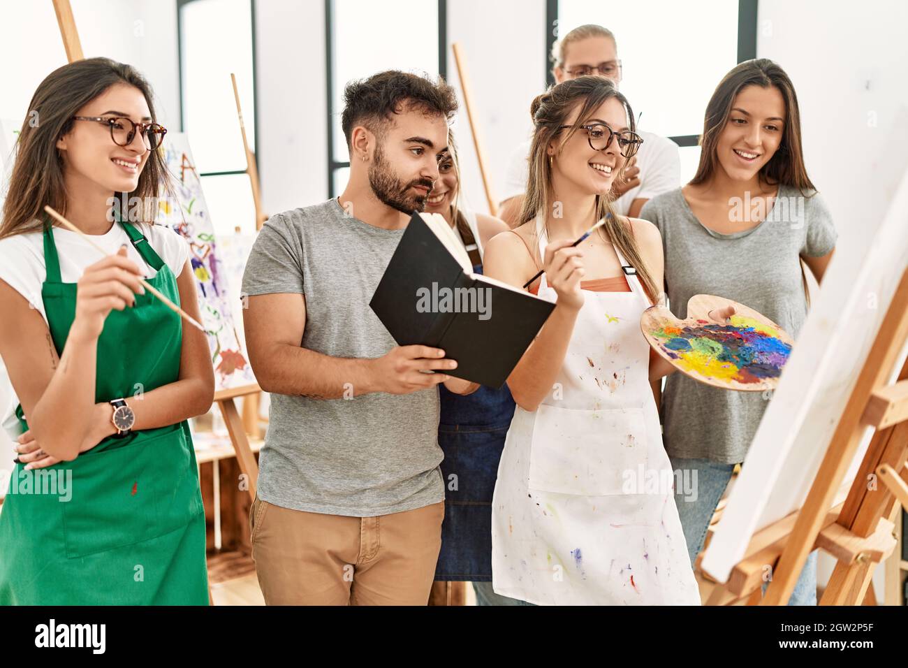 Group of young paint students smiling happy and looking draw of partner ...