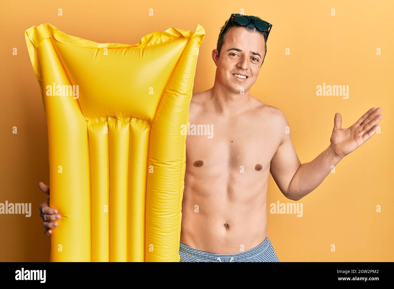 Handsome young man wearing swimsuit and holding summer float ...