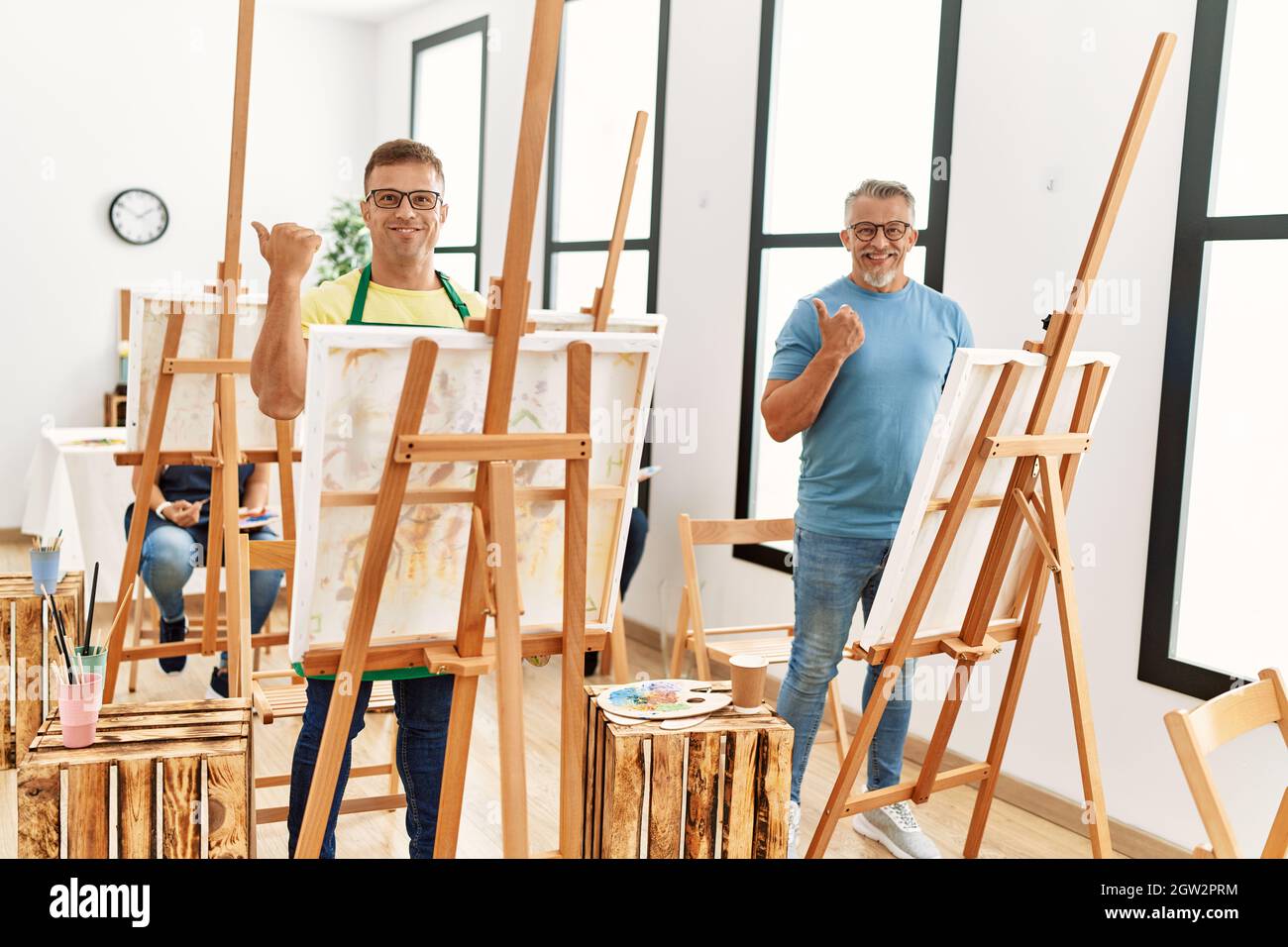 Group of middle age people artist at art studio pointing thumb up to ...