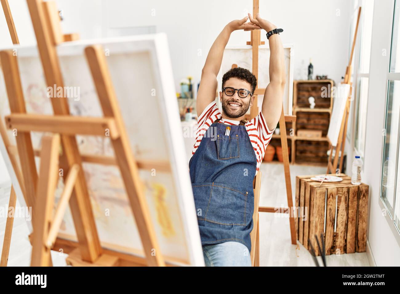 Young arab artist man stretching arms at art studio Stock Photo - Alamy