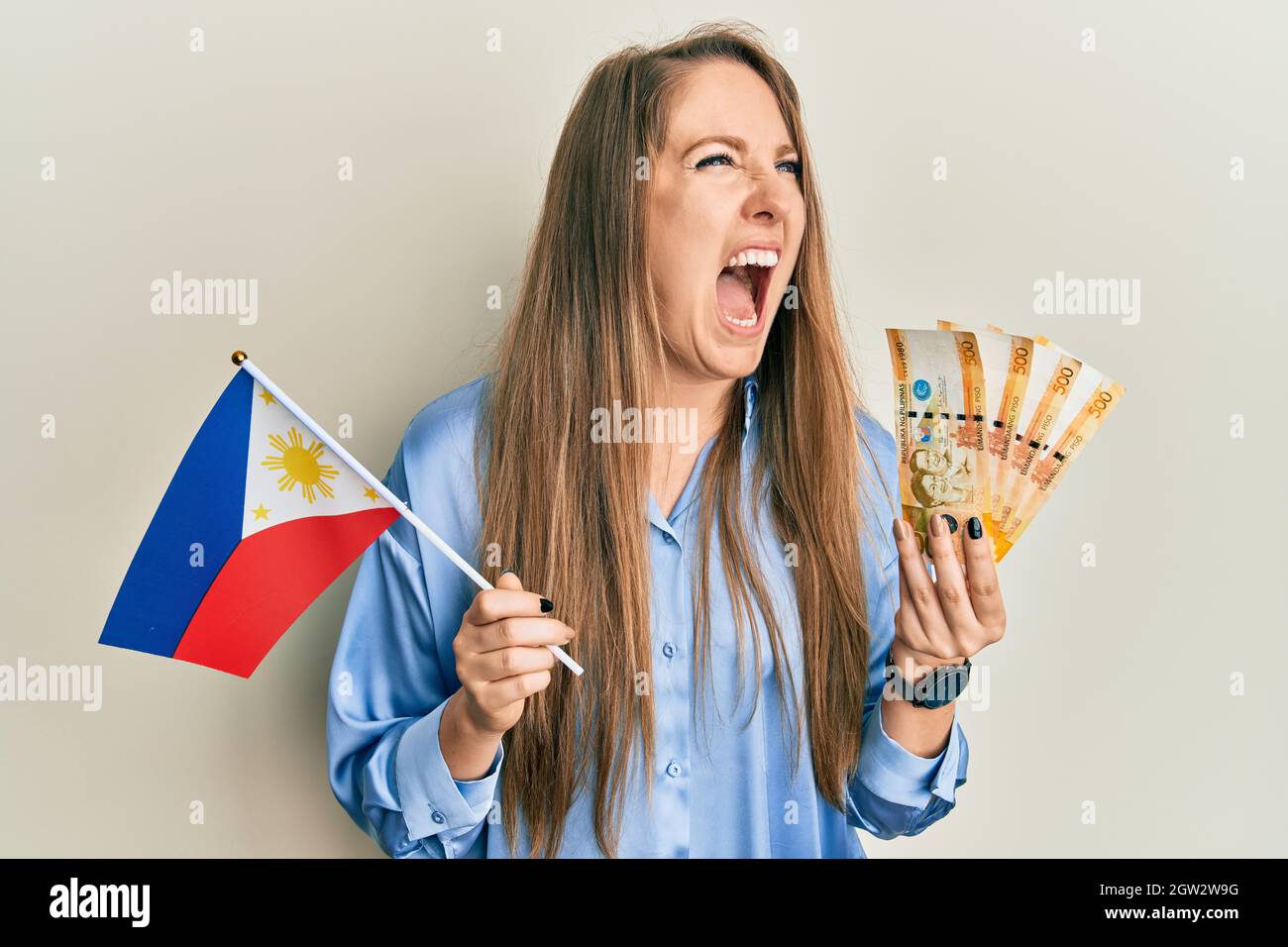 Young blonde woman holding philippine flag and philippines pesos ...
