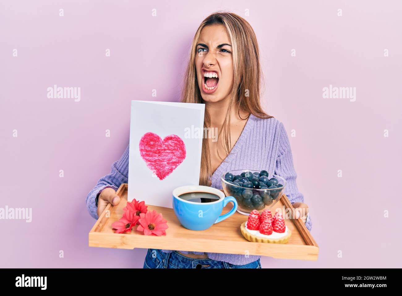 Beautiful hispanic woman holding tray with breakfast and heart card ...