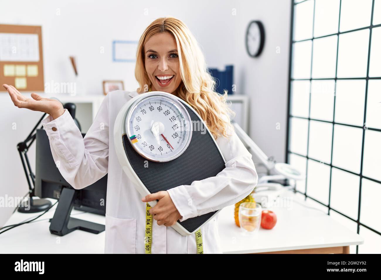 Beautiful blonde nutritionist woman holding weight machine to balance ...