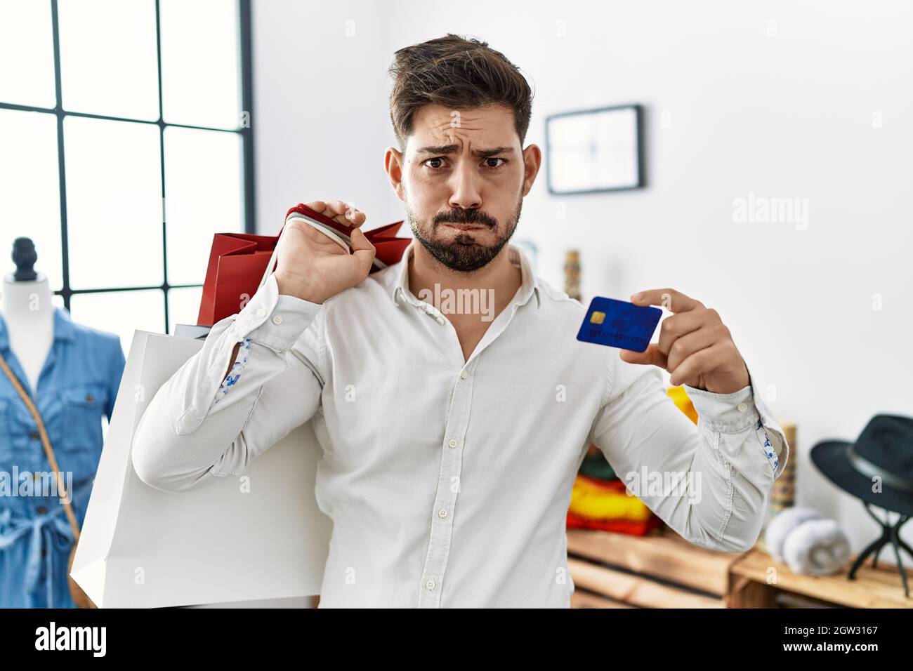 Young man with beard at retail shop holding shopping bags and credit ...