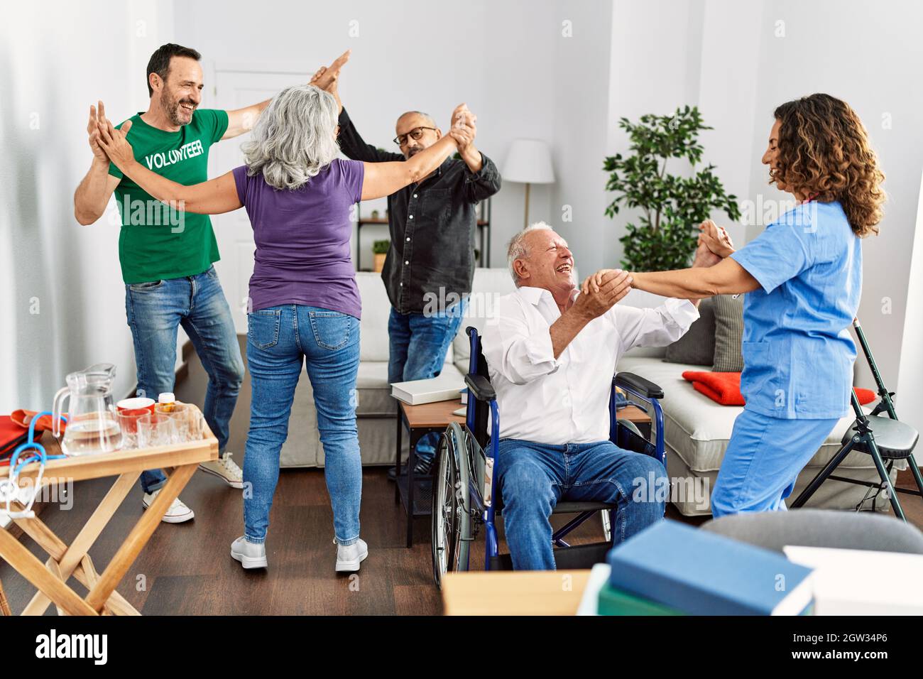 Group of retired people having party dancing with doctor and volunteer ...