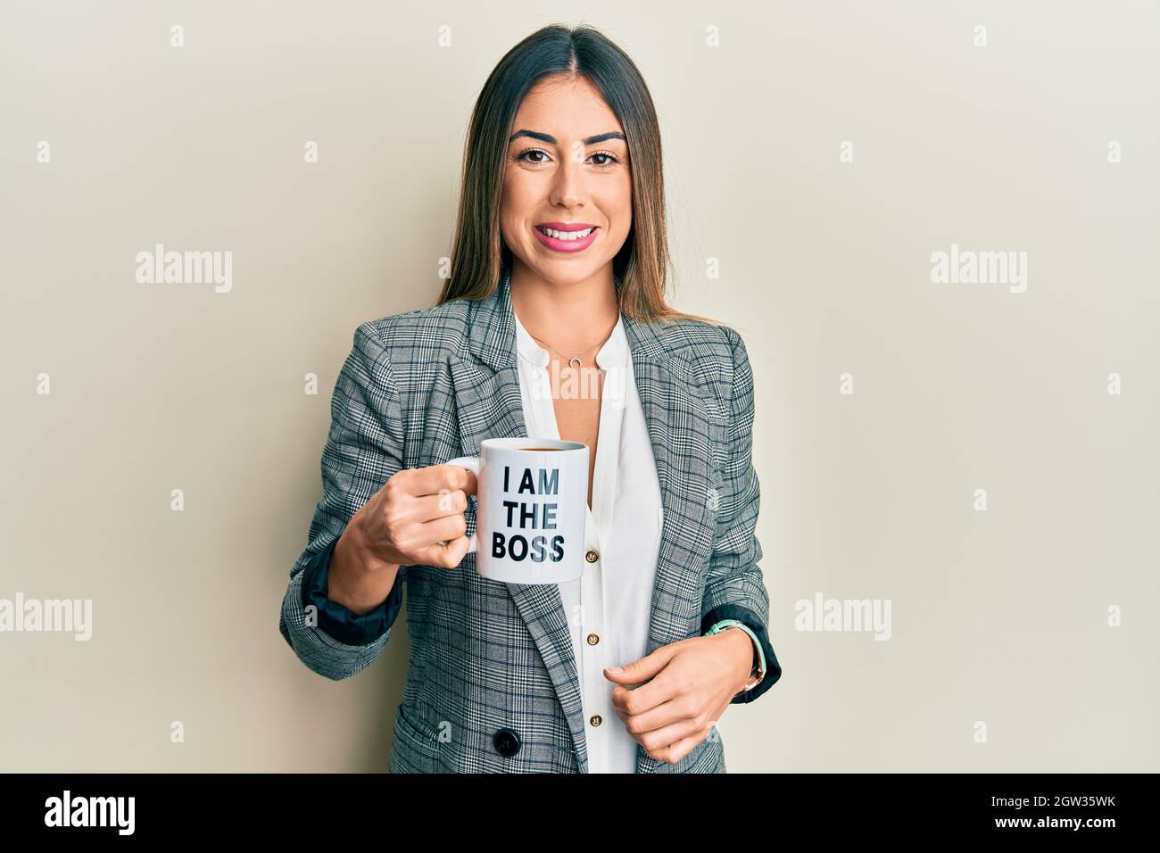 Young Hispanic Woman Drinking From I Am The Boss Coffee Cup Looking