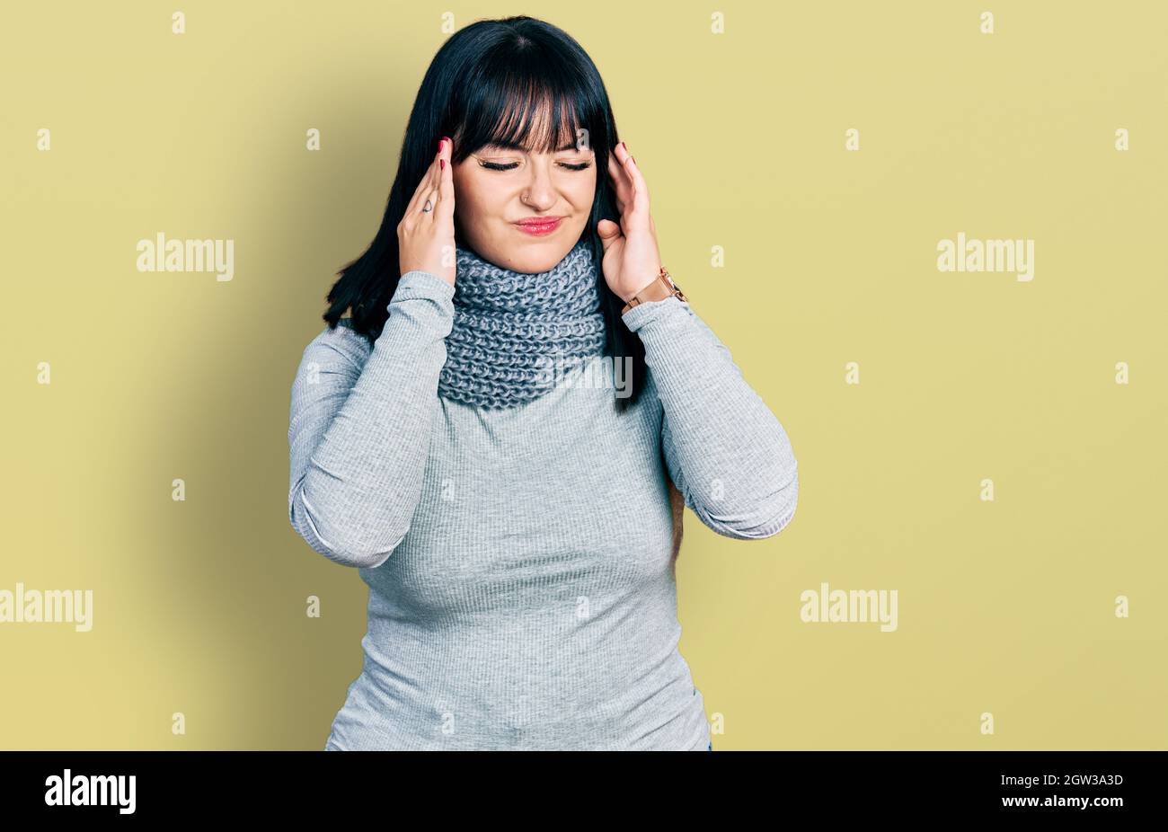 Young hispanic plus size woman wearing winter scarf with hand on head ...