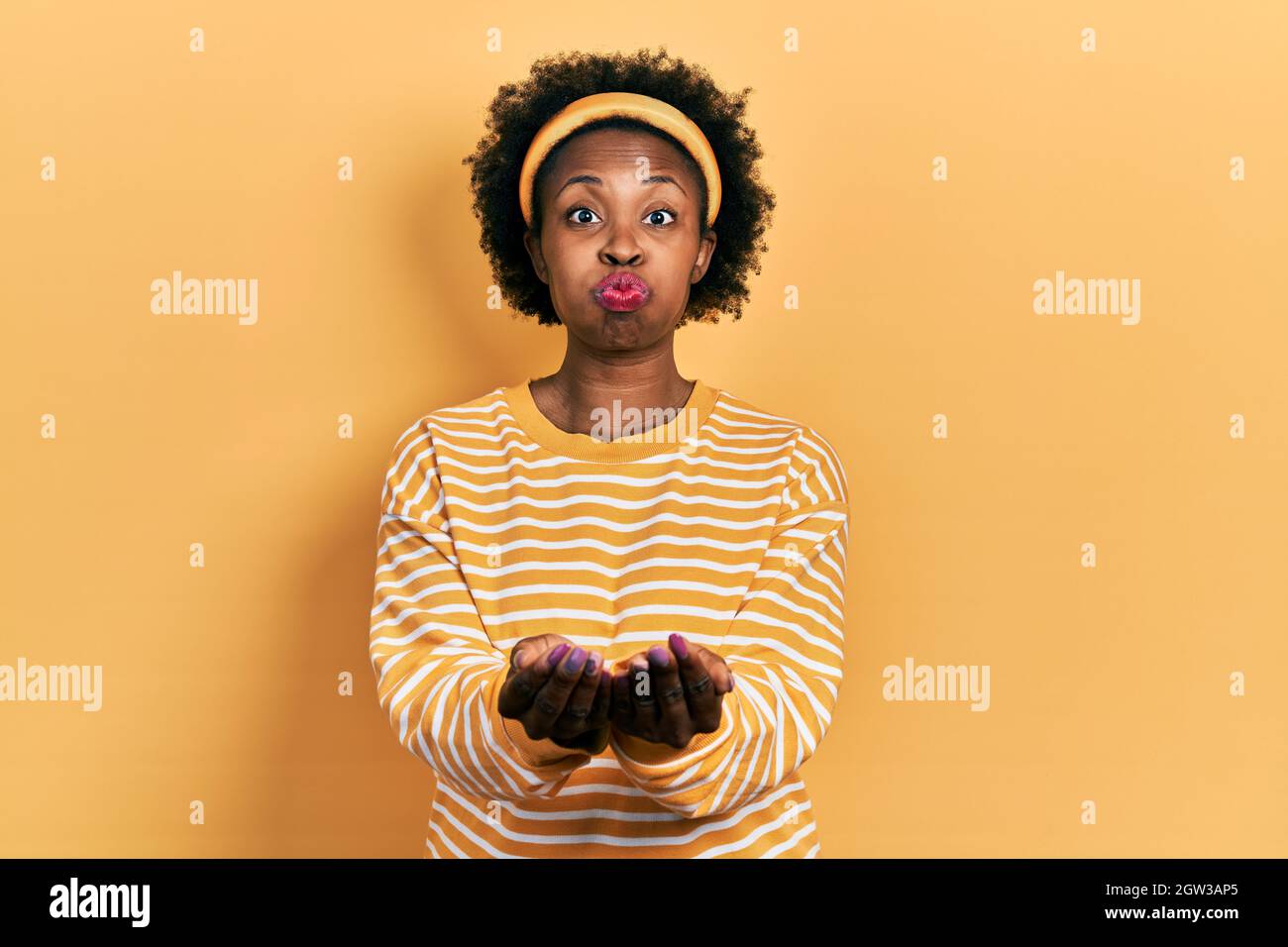Young african american woman holding hands together cupped, giving ...