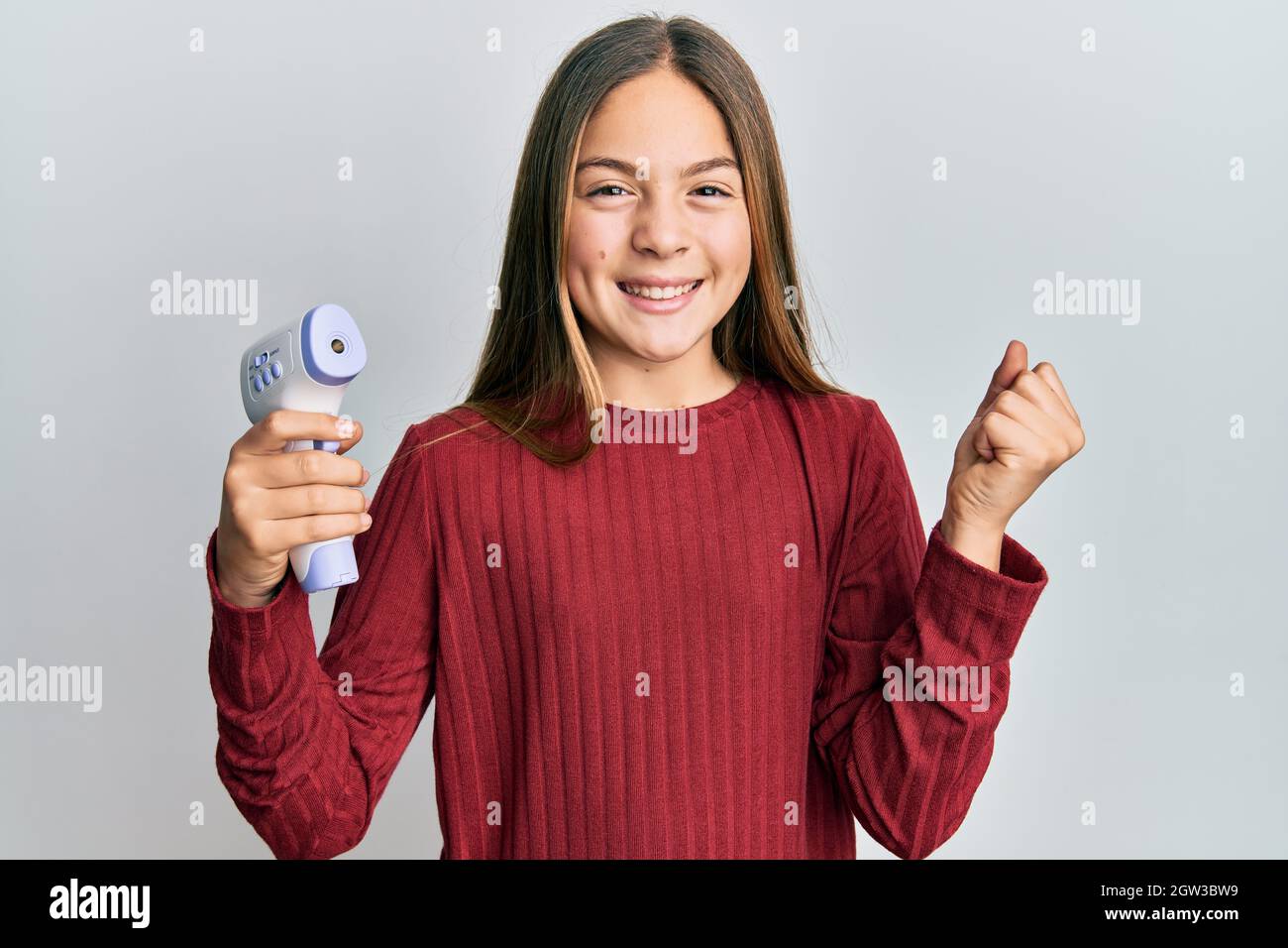 Beautiful brunette little girl holding thermometer screaming proud ...