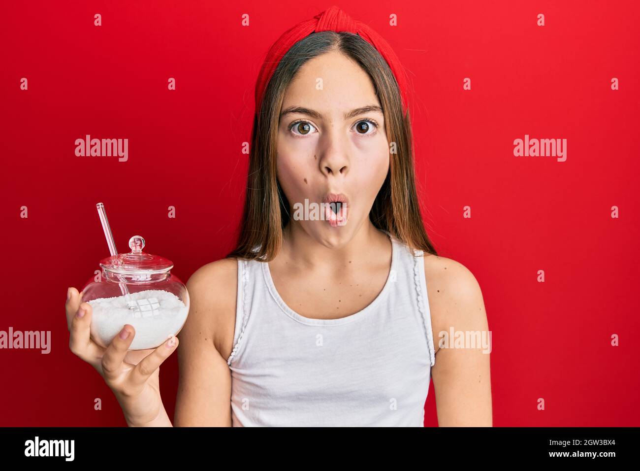 Beautiful brunette little girl holding bowl with sugar scared and ...