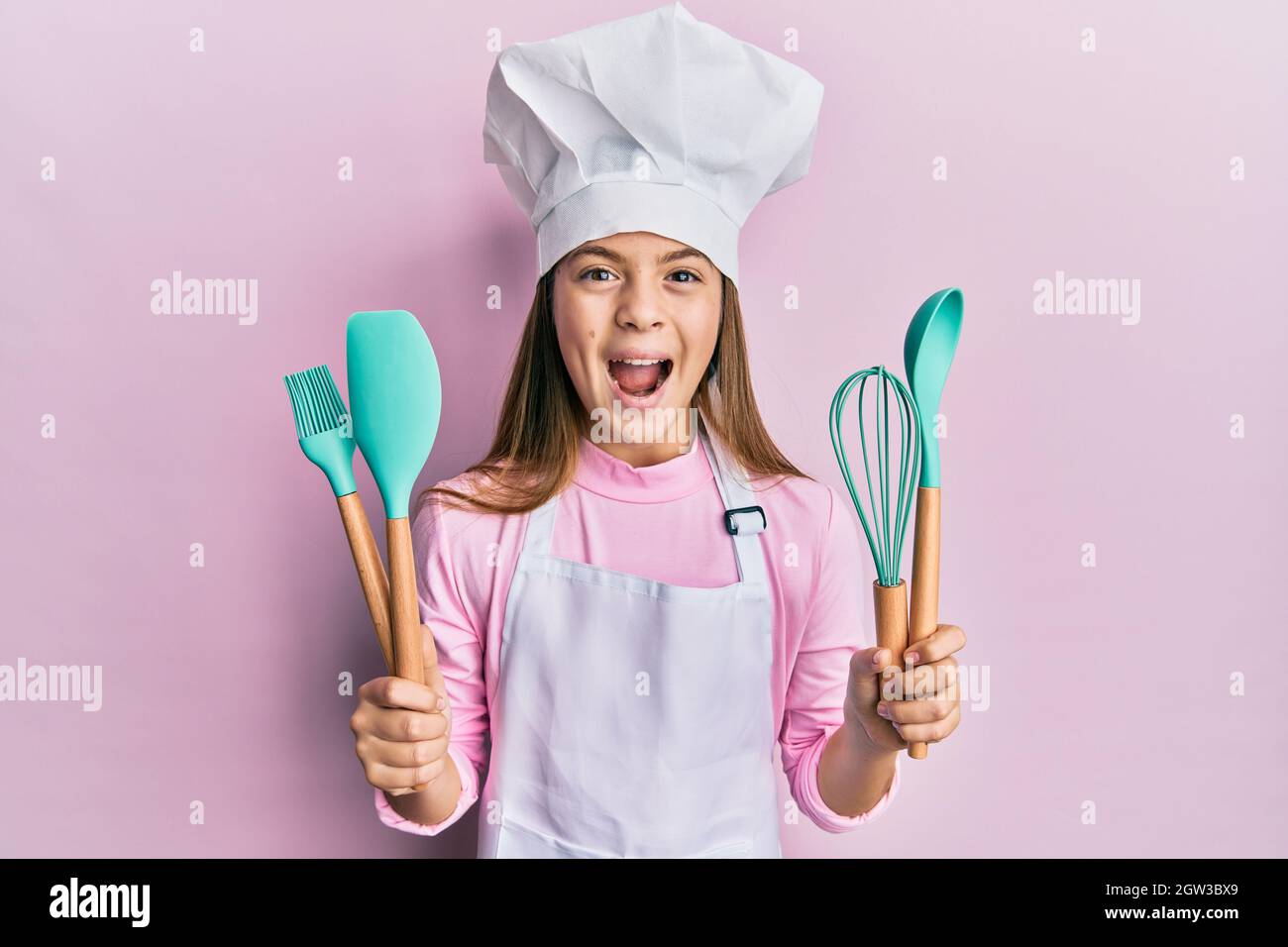 Beautiful brunette little girl wearing professional cook apron holding ...
