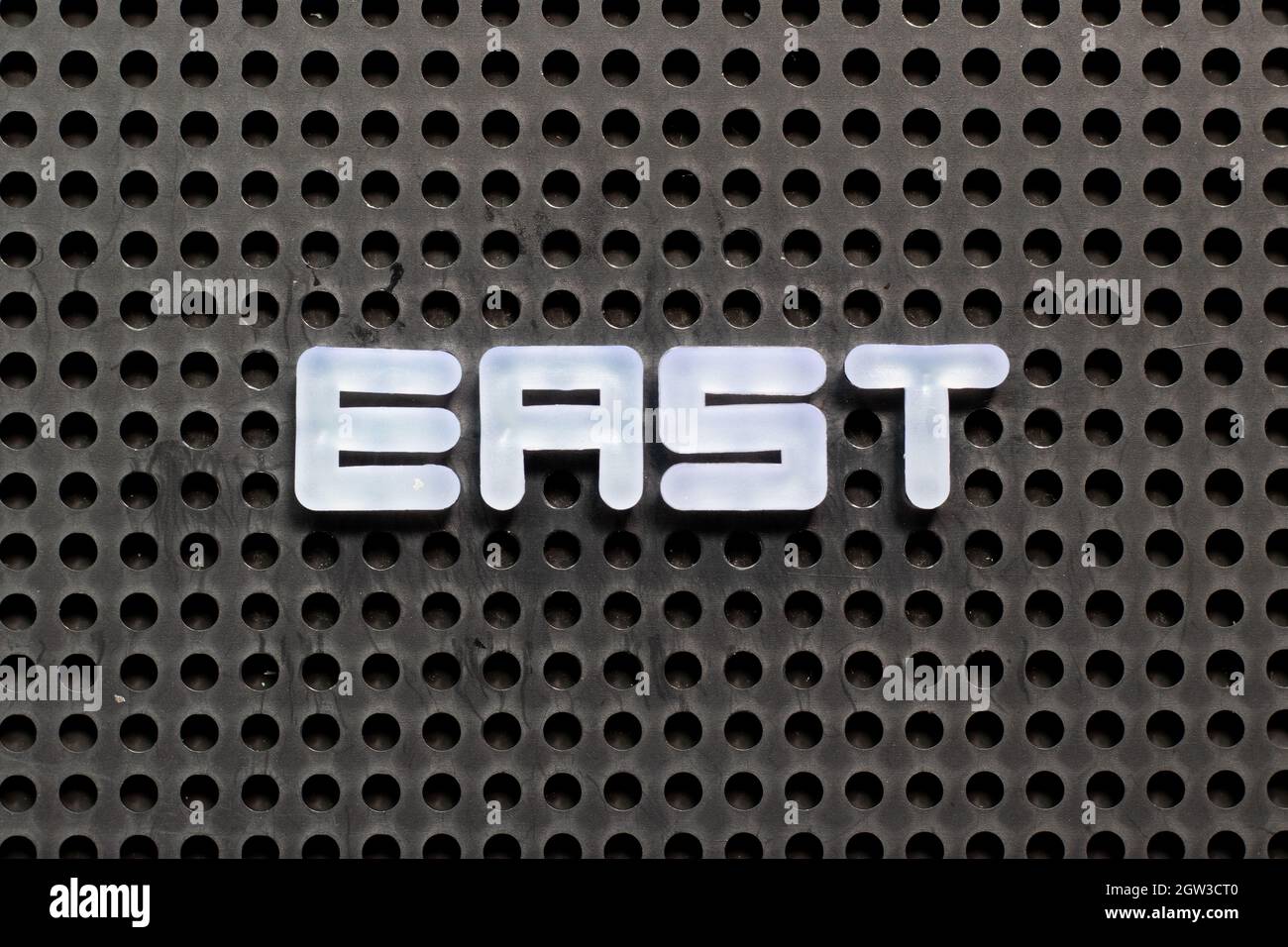White color letter in word east on black pegboard background Stock ...