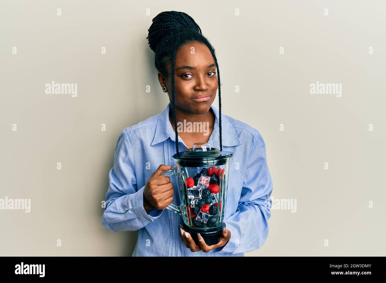 African american woman with braided hair holding food processor mixer ...